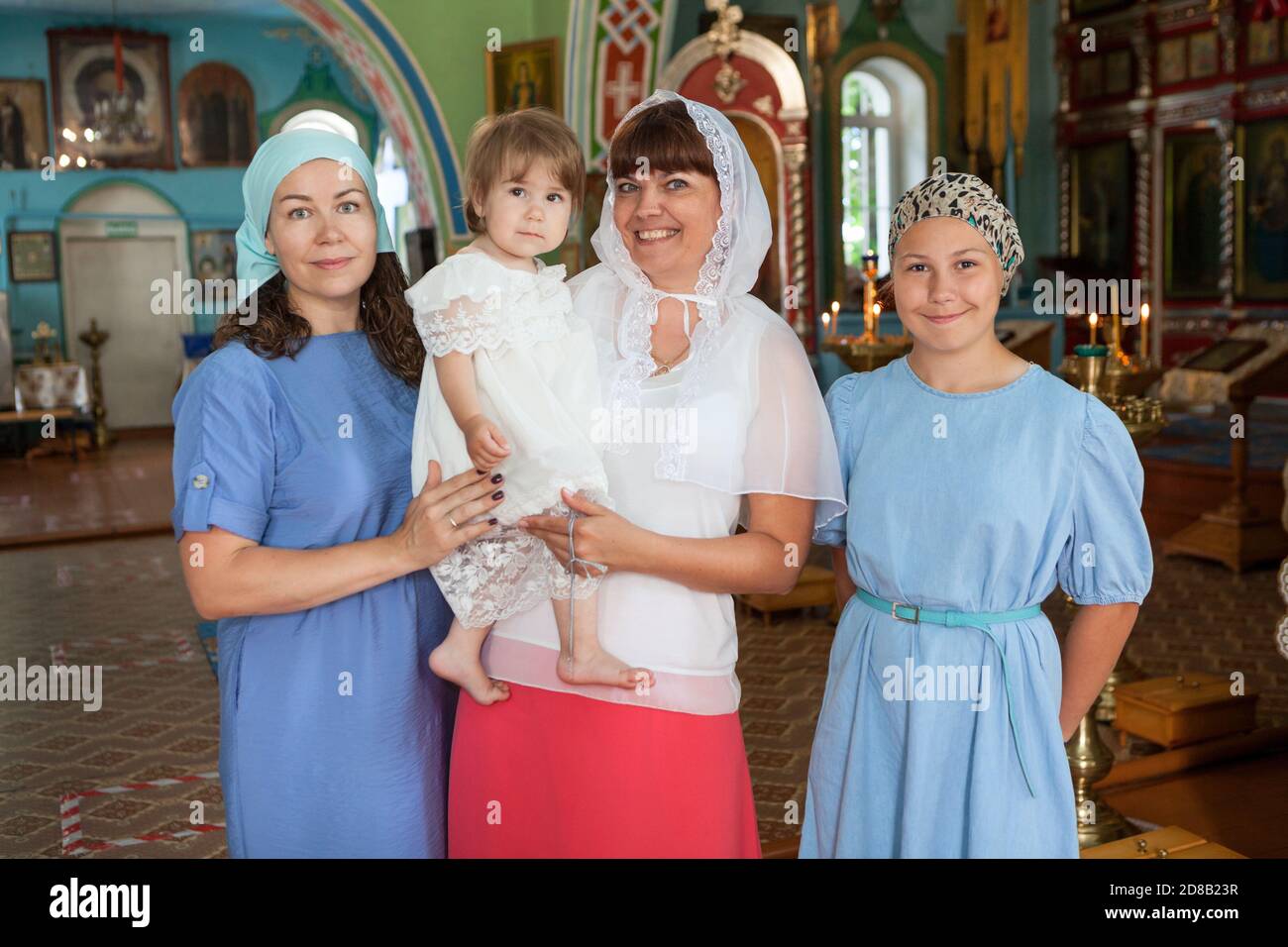 Mother with toddler and teenage daughters standing in church, godmother ...