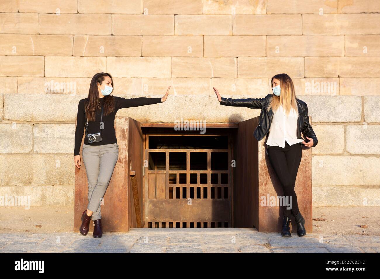 Two friends wearing a face protection mask delimiting the social ...