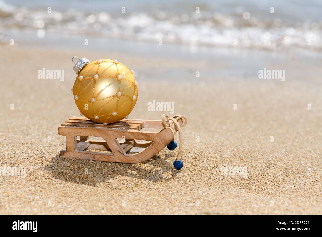 Christmas sled with golden ball on the tropical beach near ocean, a ...