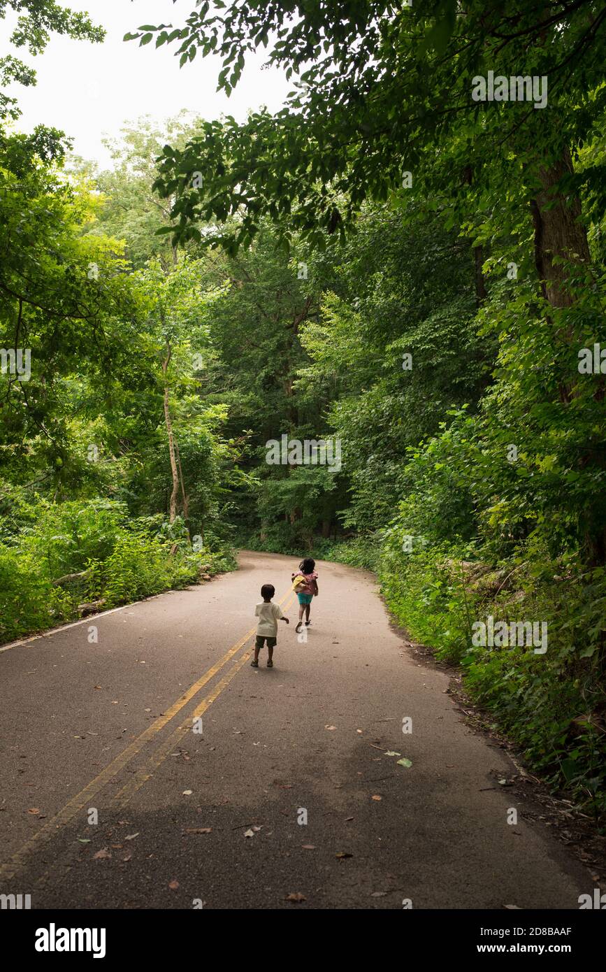 Kids running down a road with trees on both sides Stock Photo - Alamy