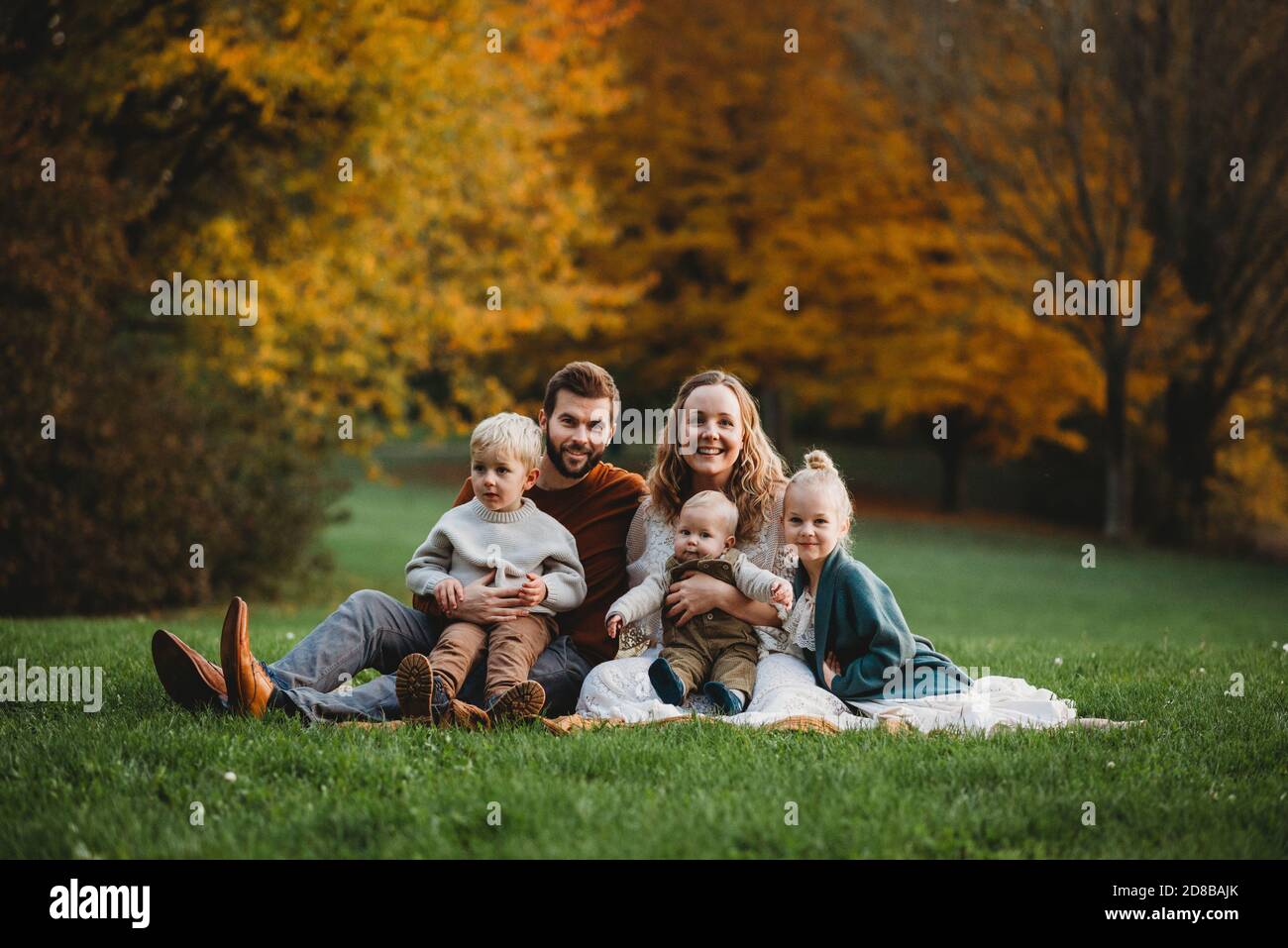 Good looking family sitting in a park with colorful Fall trees Stock ...