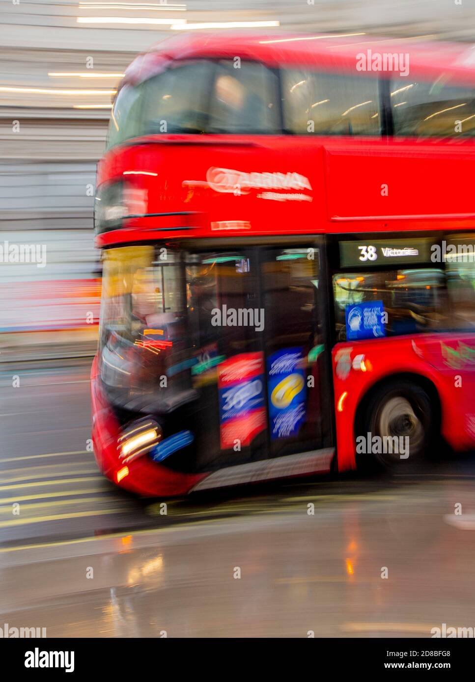 Red London bus moving fast along Piccadilly; rainy afternoon, wet ...
