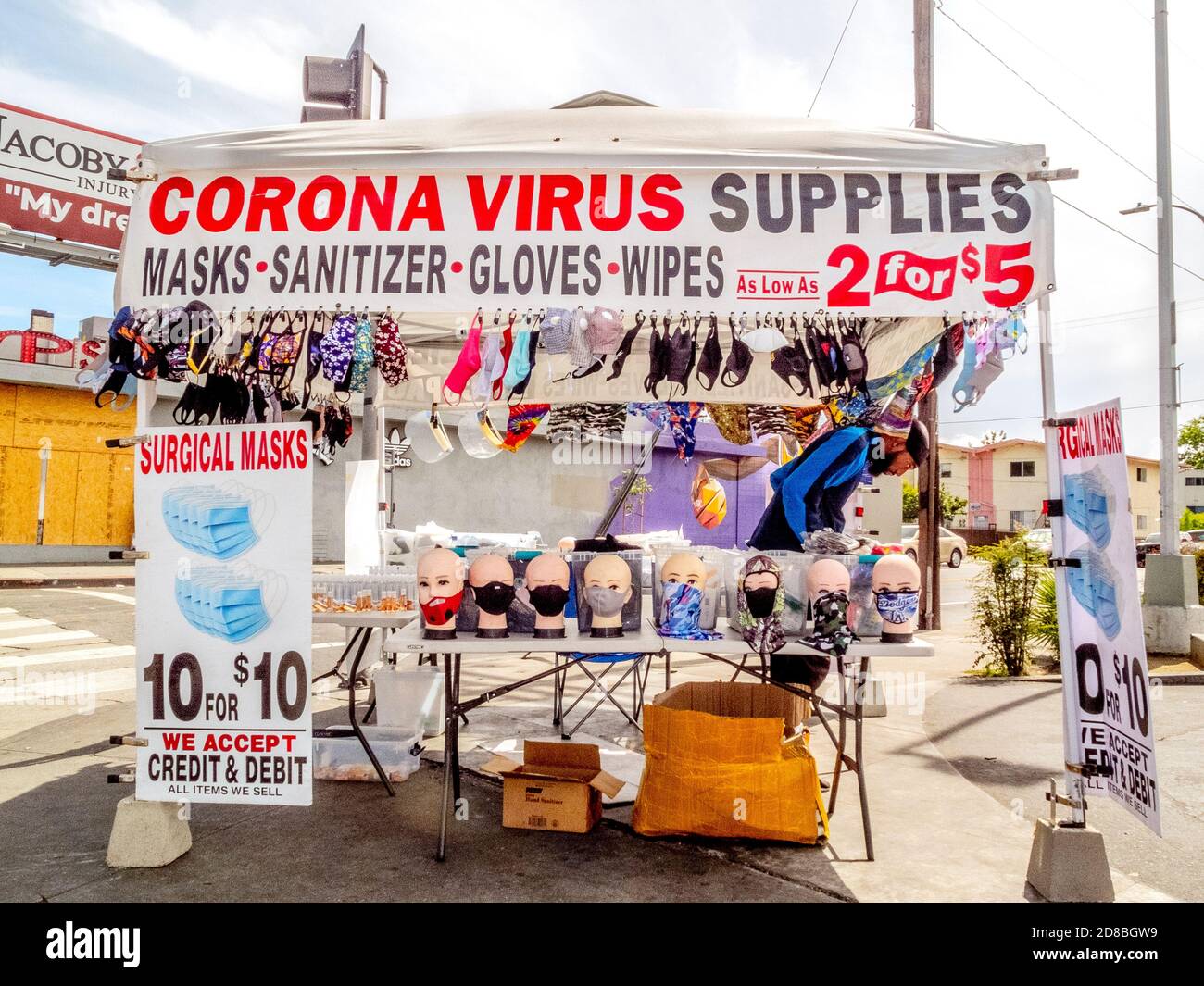 A Hispanic salesman mans a street display of colorful face masks during ...