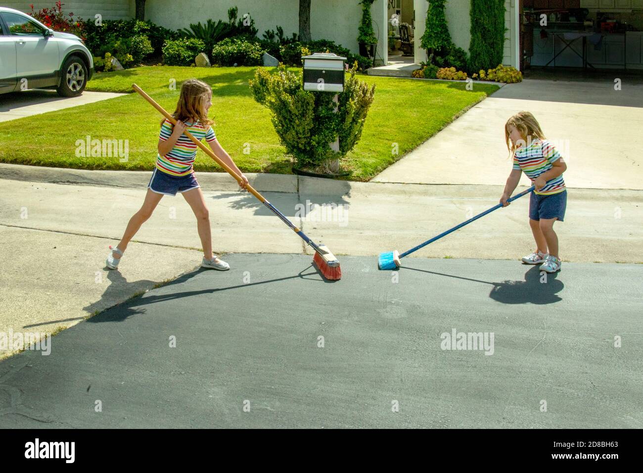 Identically dressed sisters sweep the driveway of their family home in ...