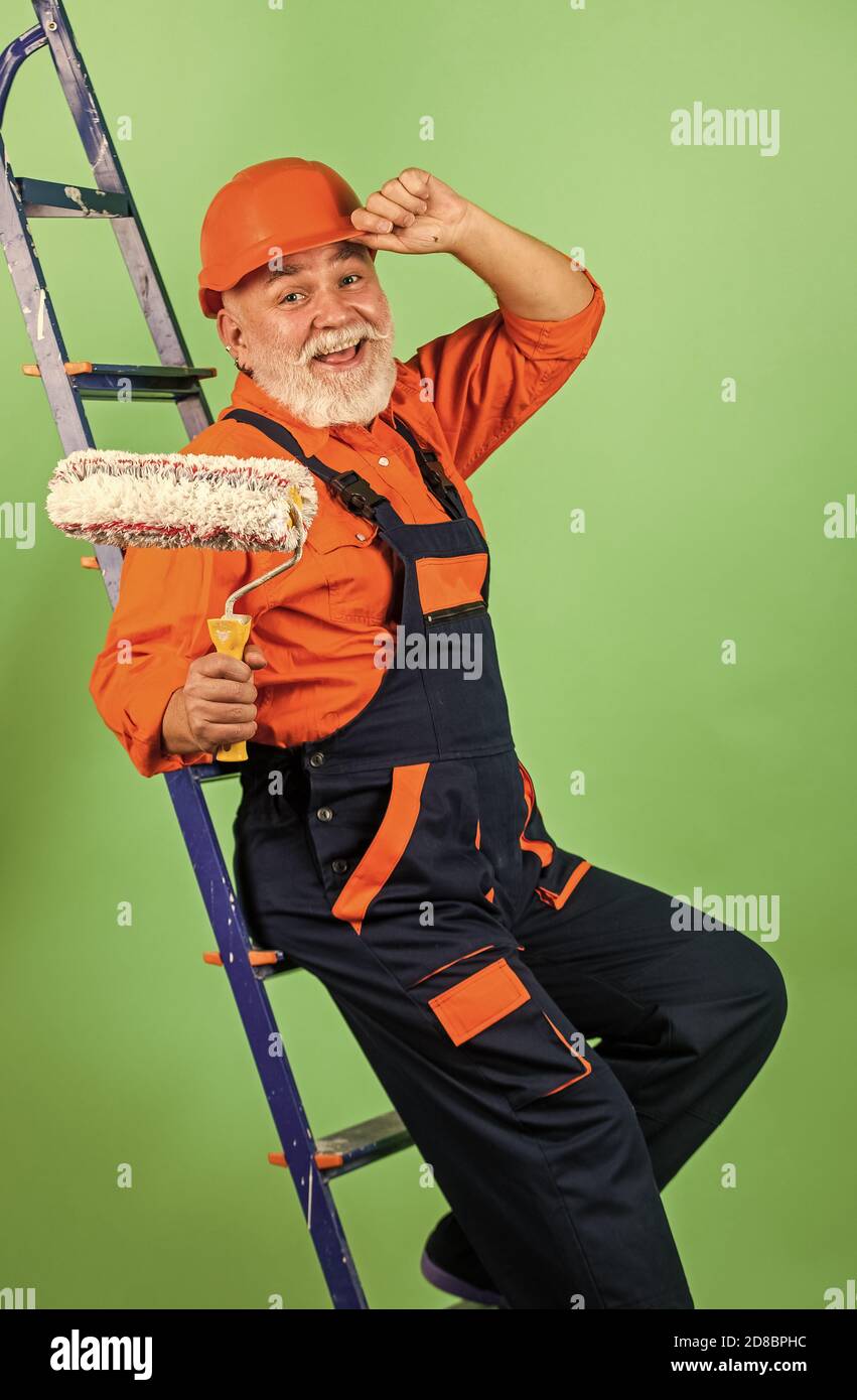 construction site engineer. senior man painter use roller on ladder ...