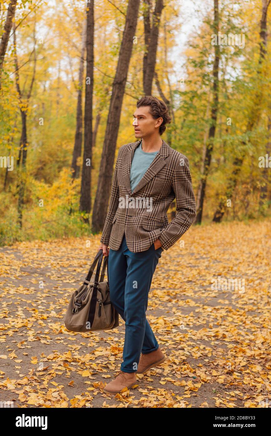 Tall handsome man with a bag on the autumn alley Stock Photo - Alamy