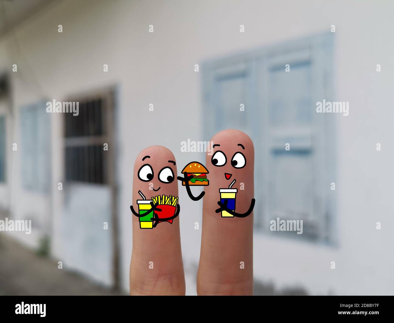 Two fingers are decorated as two person. They are having fast food ...