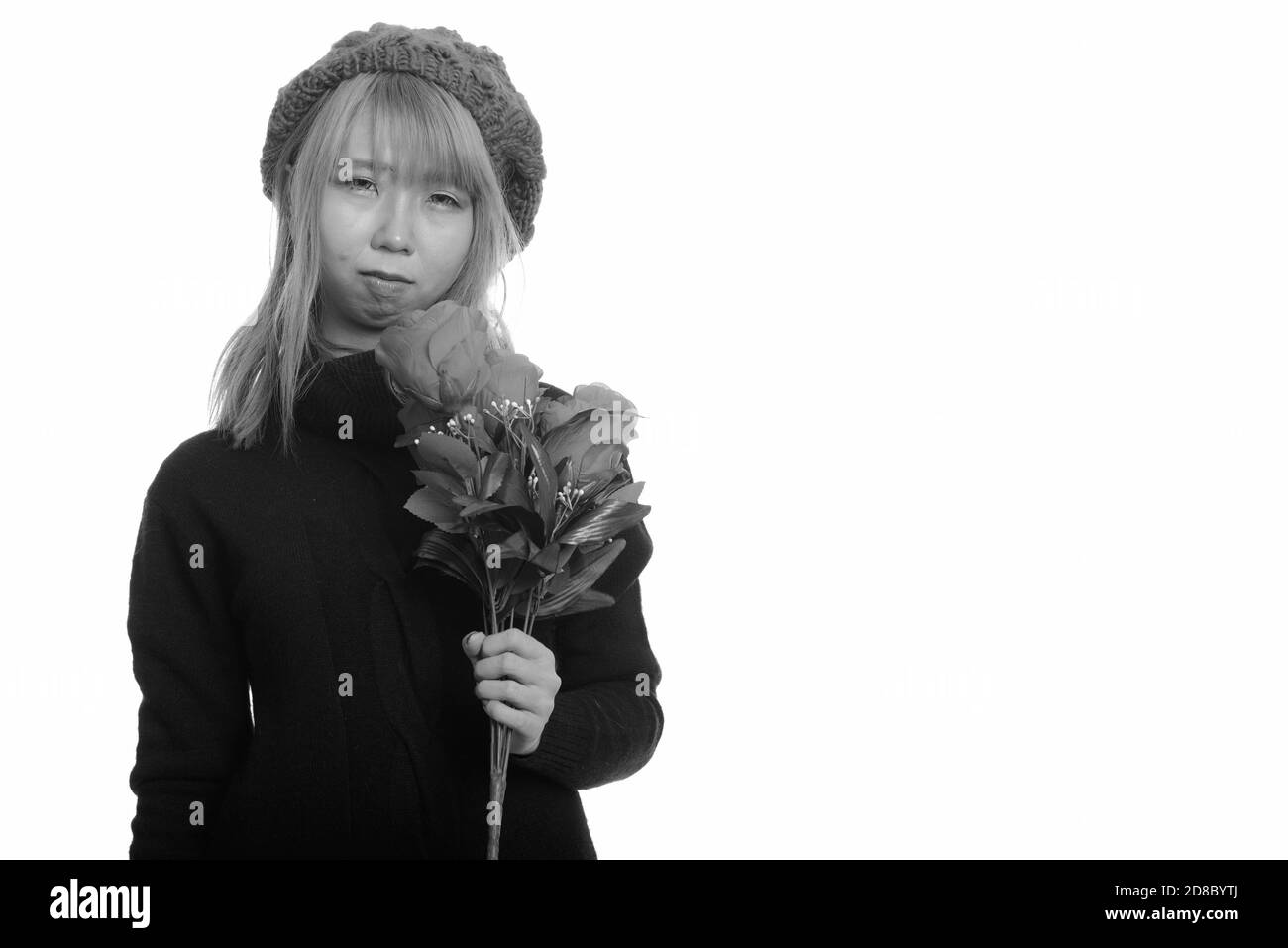 Young cute Asian woman holding roses looking upset Stock Photo - Alamy