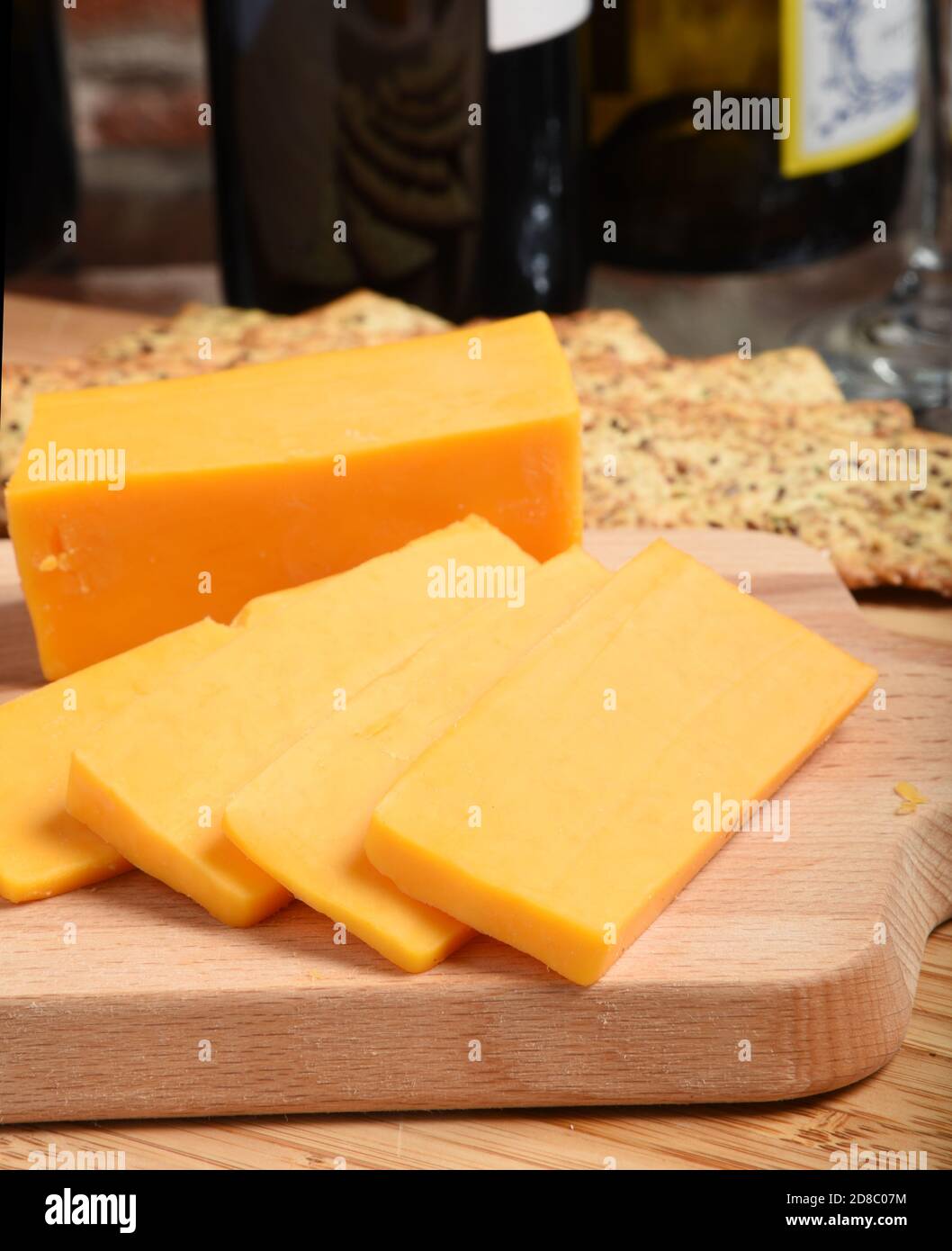 Vertical shot of sliced yellow cheddar cheese with gourmet crackers and ...