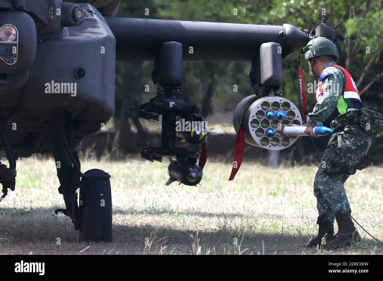 A soldier loads training rockets into a pod on an AH-64E Apache attack ...