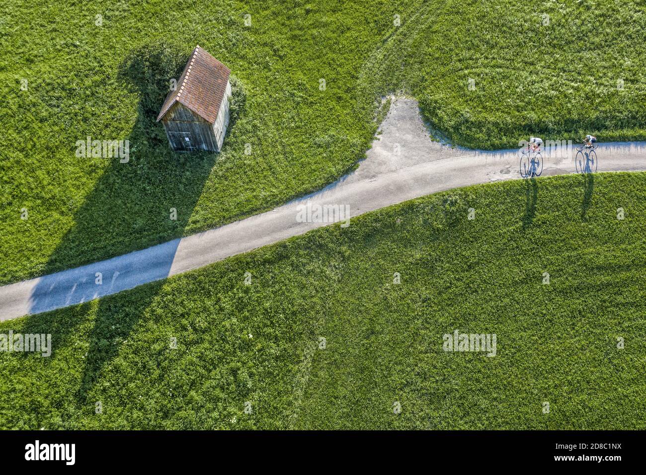 High angle shot of the cyclists cycling on the road surrounded by grass ...