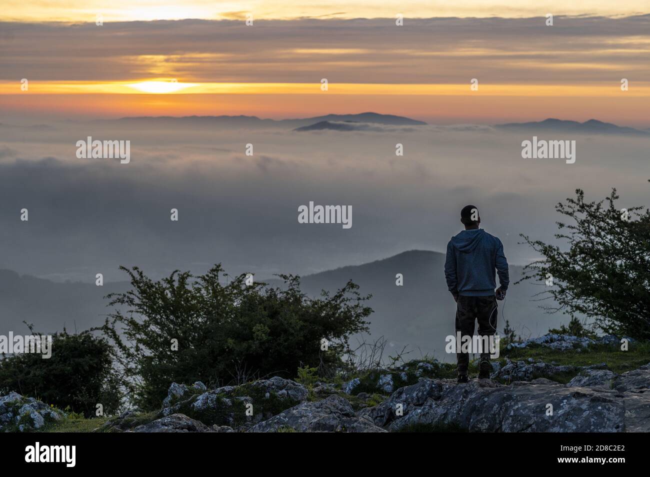 Man on a mountain looking at a beautiful sea of clouds with a rising ...