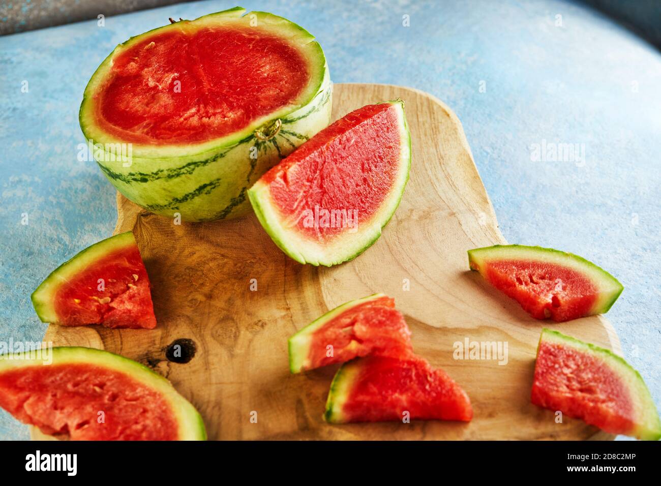 Mini Watermelon with sliced wedges on a light board on a light blue ...