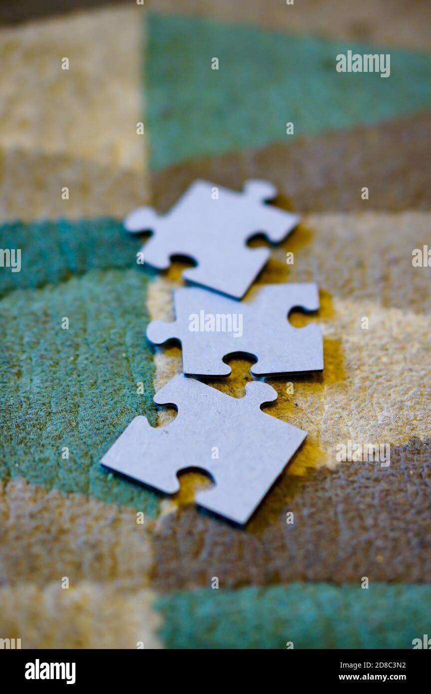Closeup of three upside-down puzzle pieces played on a colorful surface ...