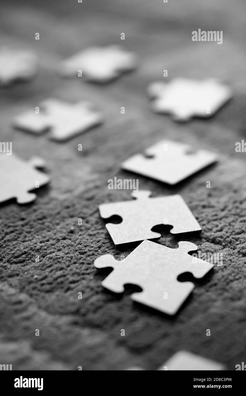 Greyscale of multiple upside-down puzzle pieces placed on a fluffy ...