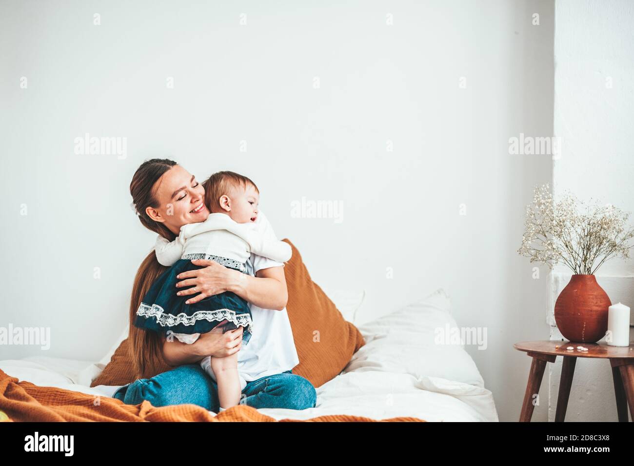Mom and baby are at home on the bed and hug Stock Photo - Alamy
