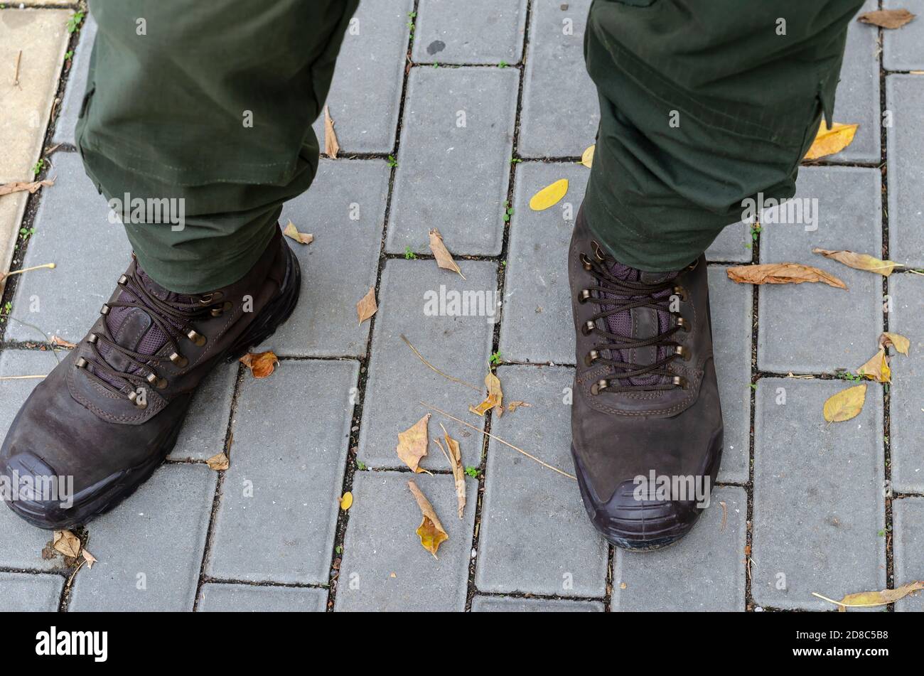Men's feet in military boots and uniform stand on the sidewalk amidst ...