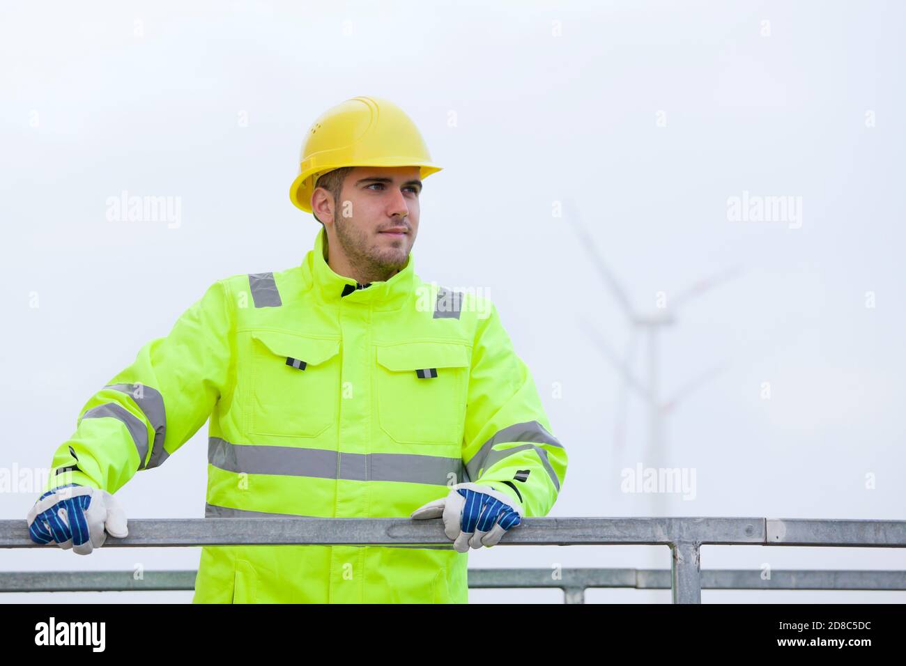 Smiling young engineer with hard hat and protective clothing in front ...