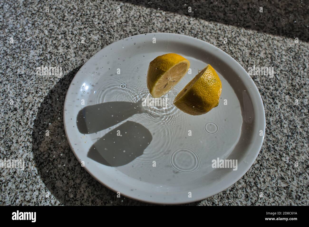 Lemon cut in half in motion with light entering from the right side ...