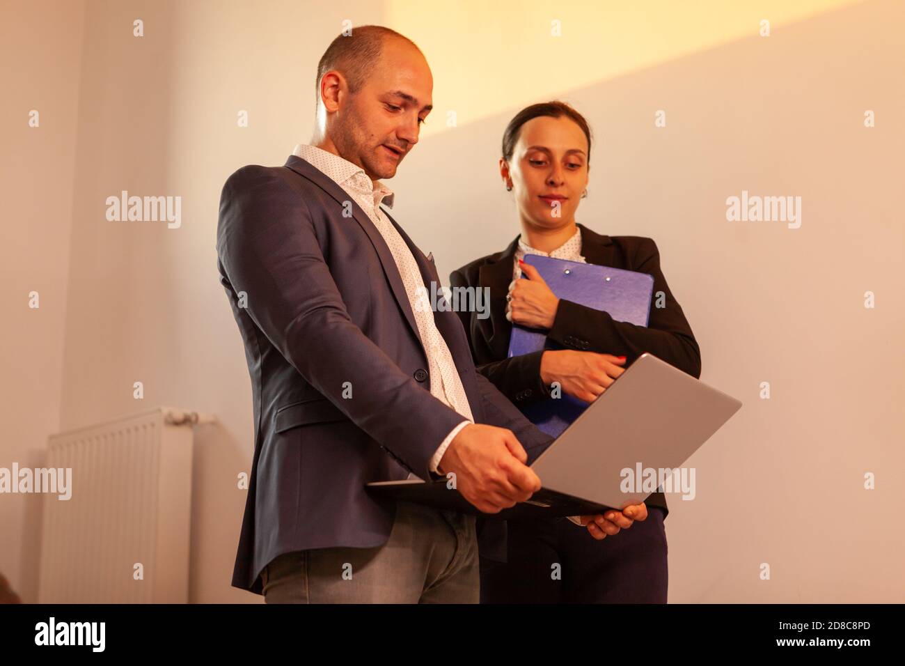 Corporate executive manager holding laptop talking with businesswoman ...