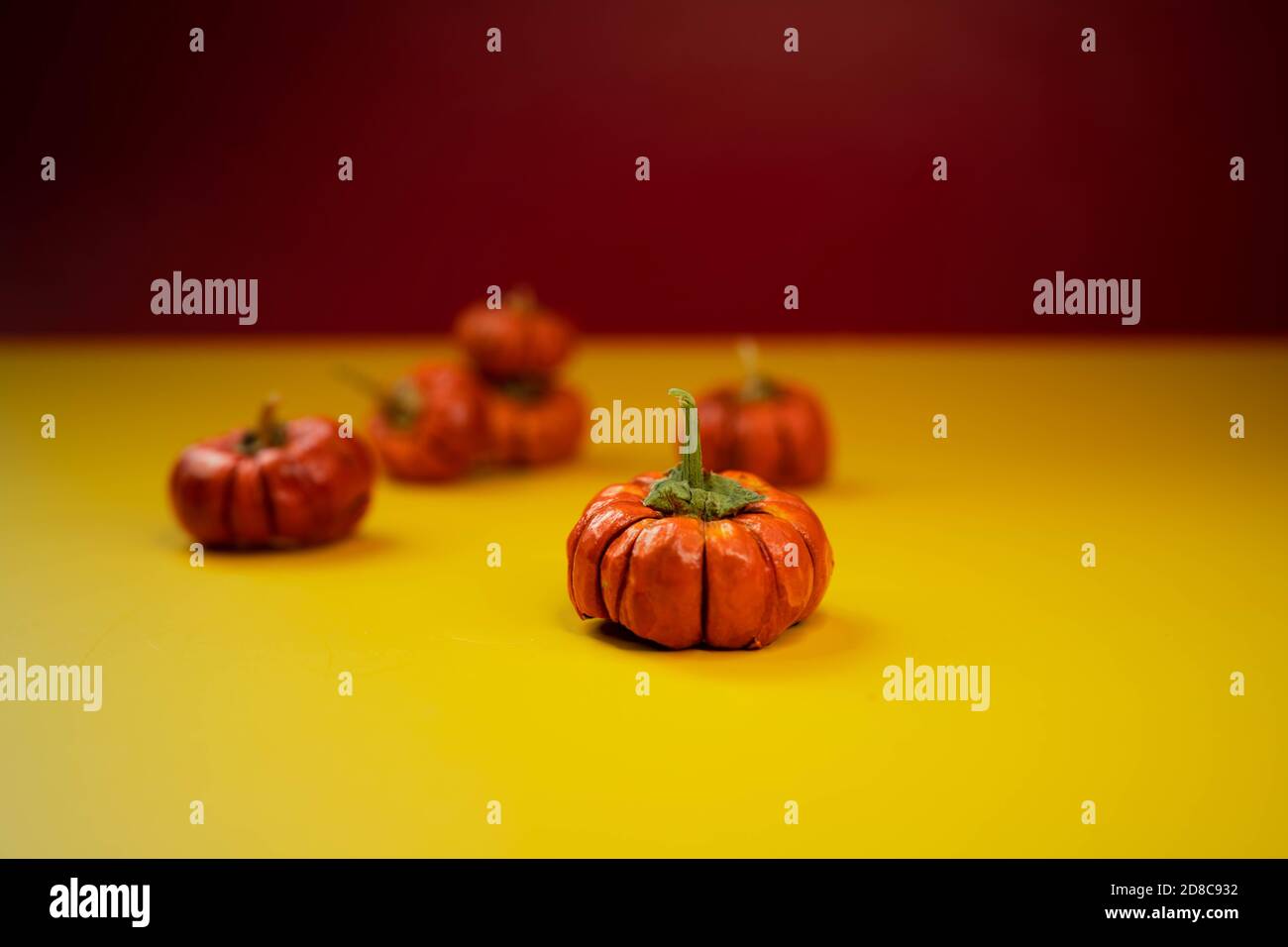 Group of little pumpkins over yellow surface and red background Stock ...