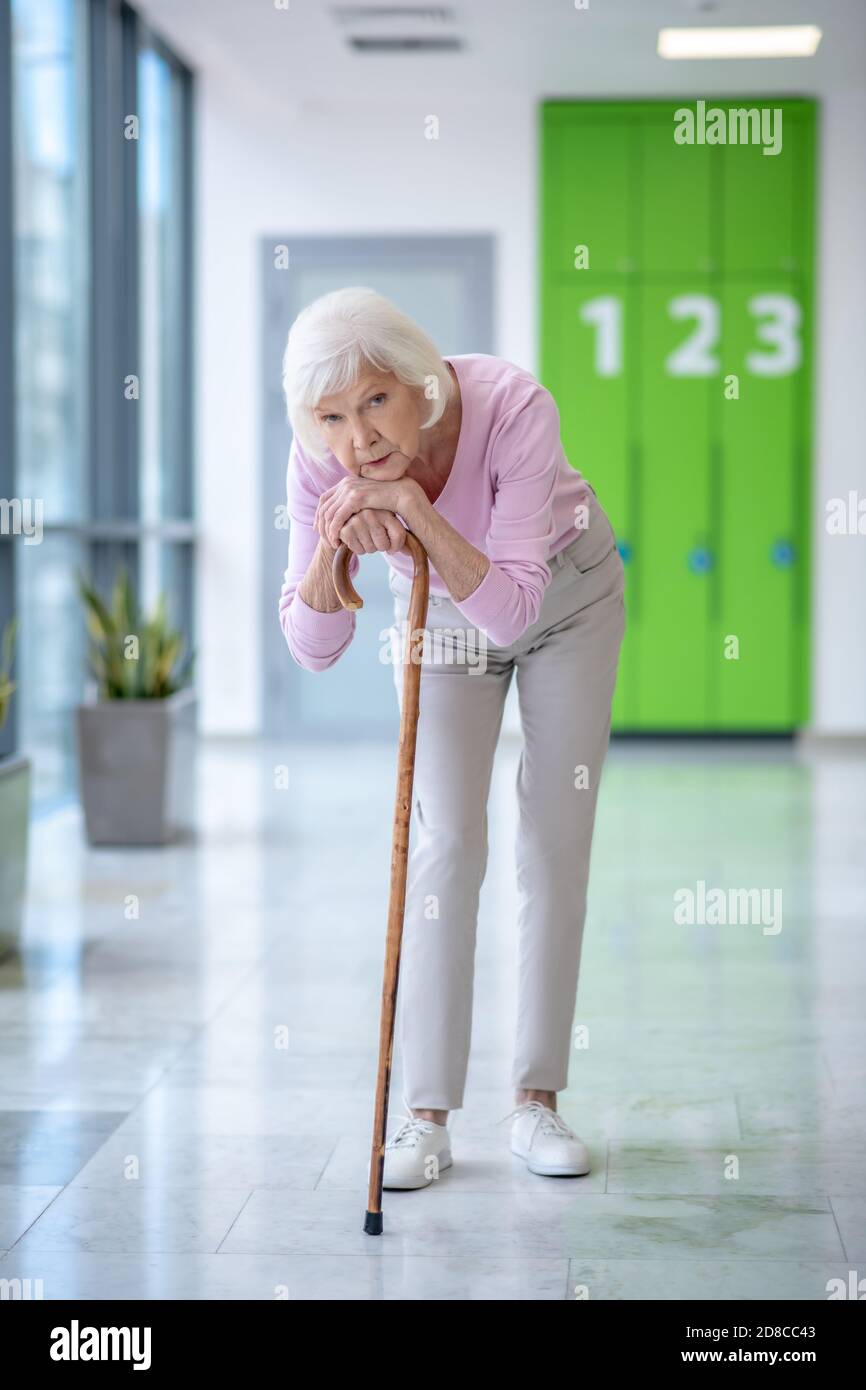 Old woman with a walking stick standing in the corridor Stock Photo - Alamy