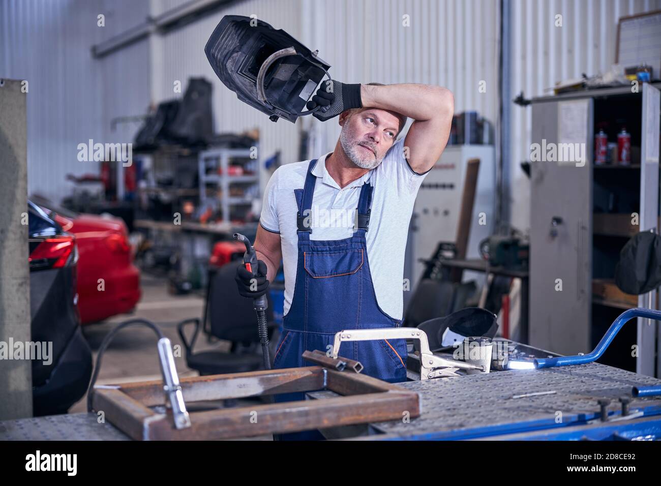 Handsome mechanic holding welding torch and protective helmet Stock ...
