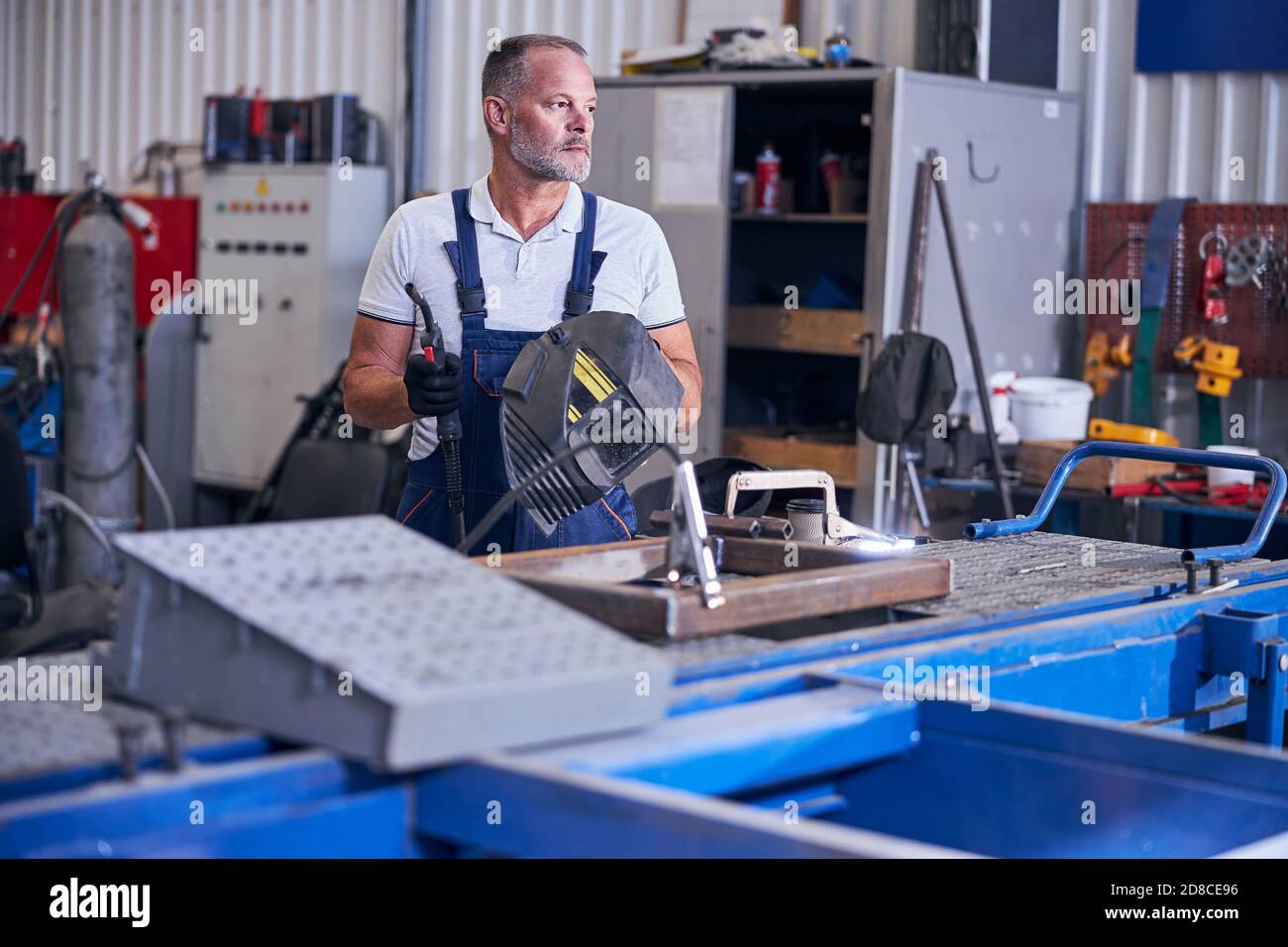 Handsome mechanic holding welding torch and welding helmet Stock Photo ...