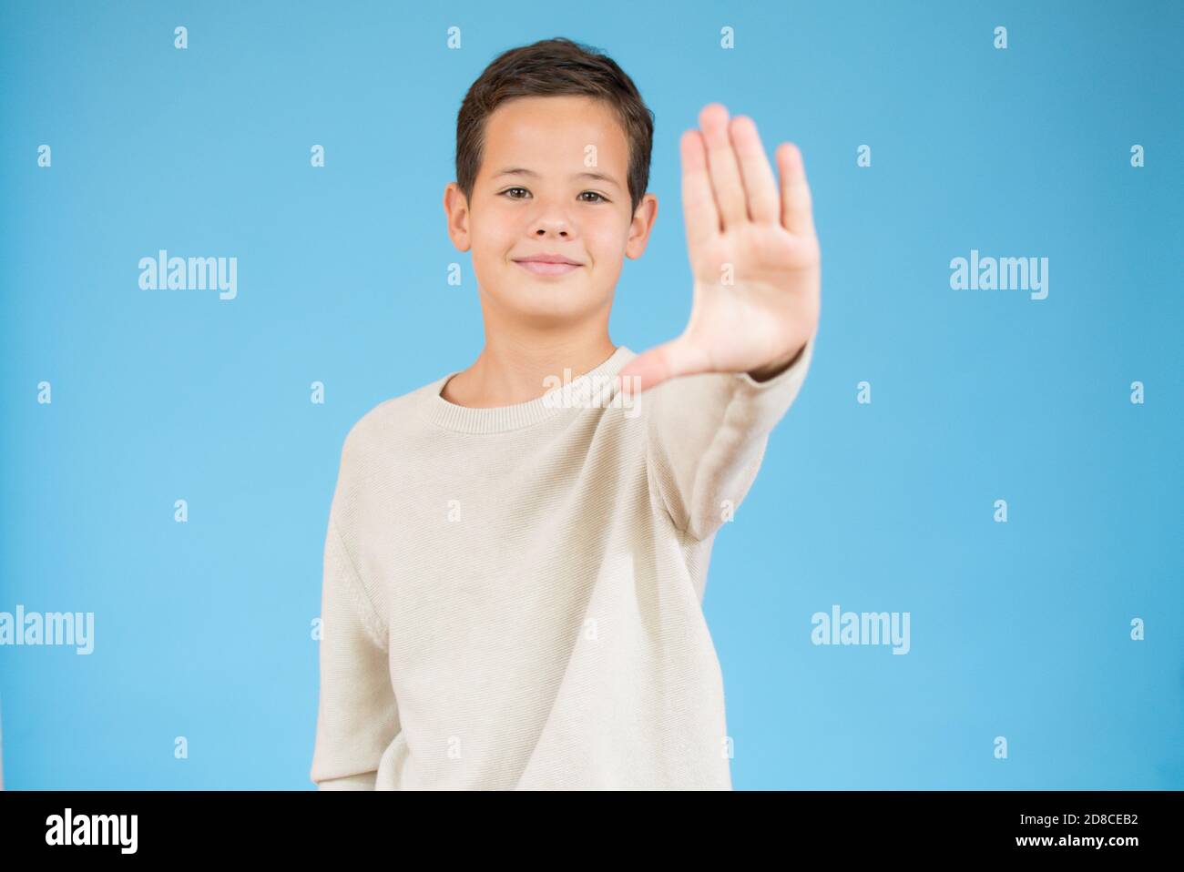 Boy making stop gesture with his palm on blue background. Body language ...