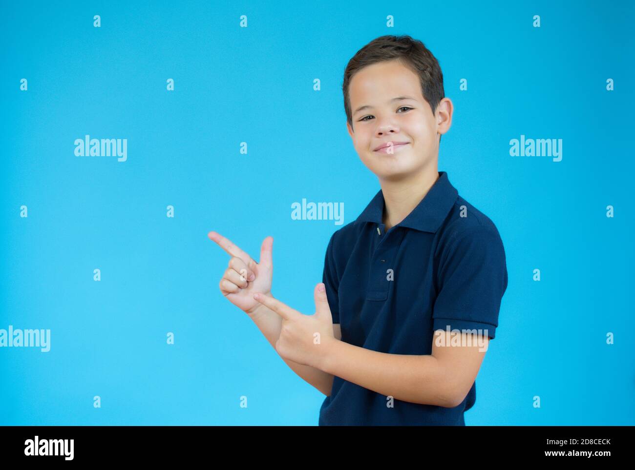 Handsome boy pointing side over blue background Stock Photo - Alamy