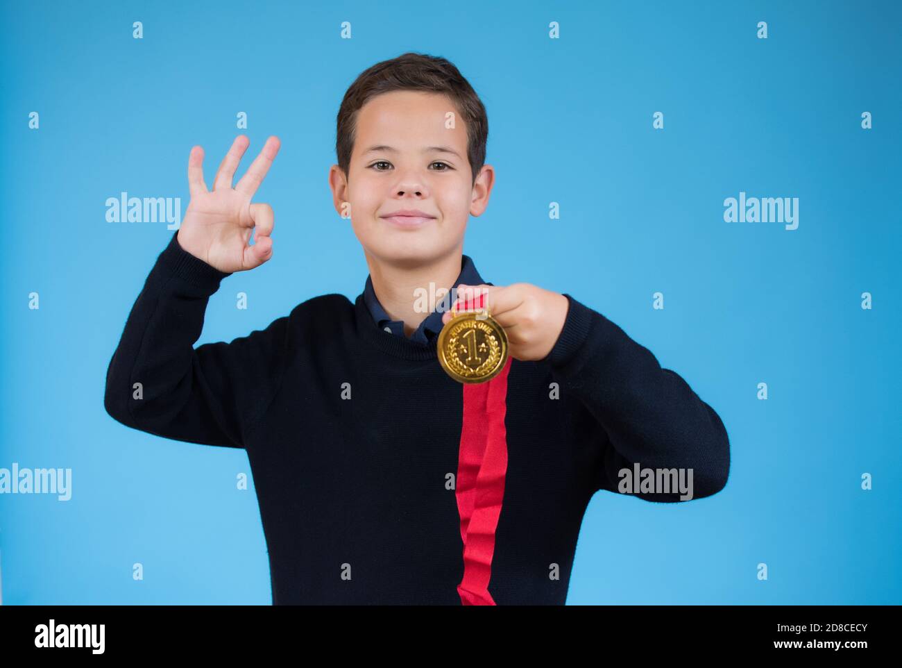 Handsome boy showing his golden medal over blue background Stock Photo ...