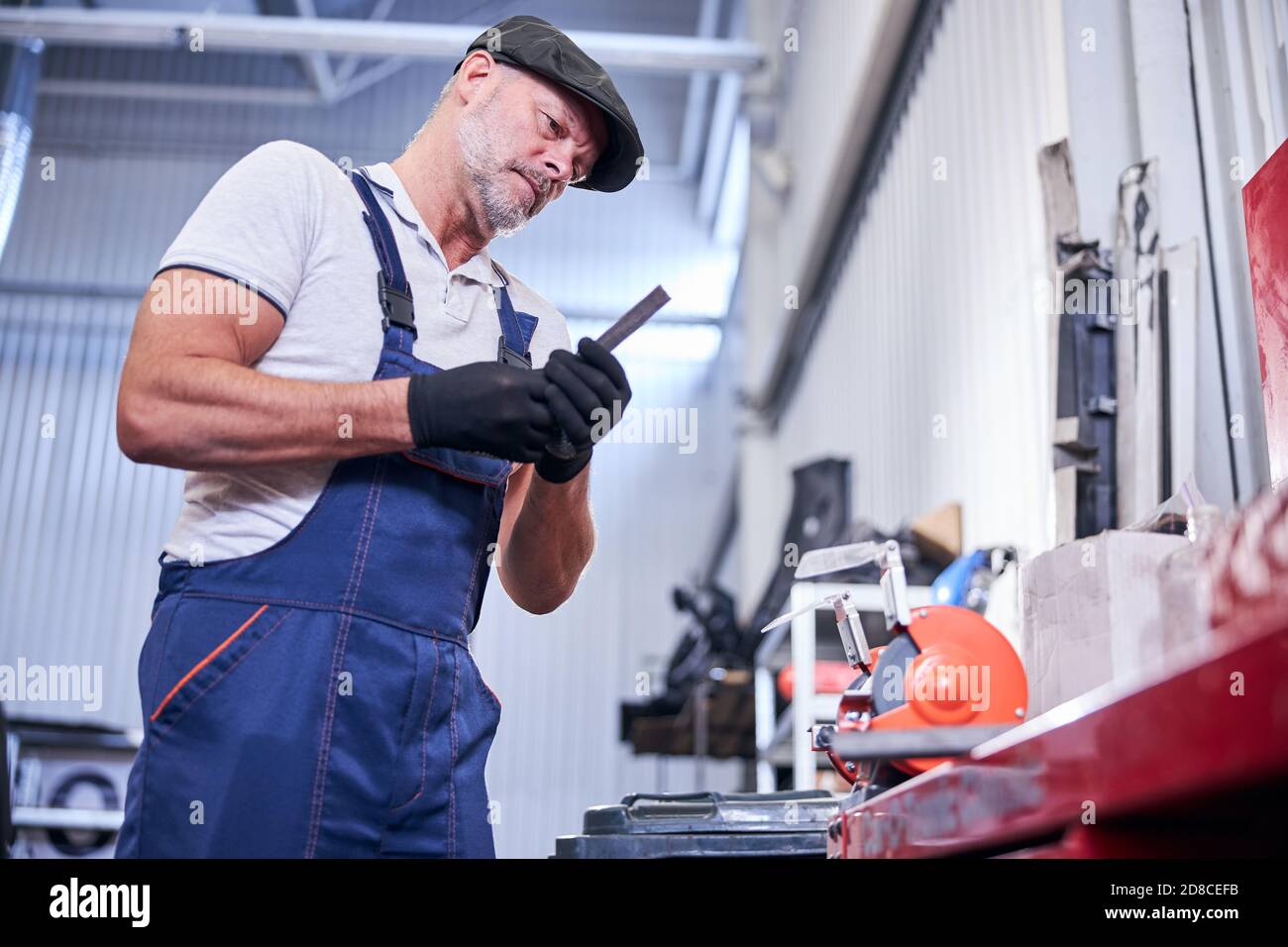Bearded mechanic grinding and polishing metal in garage Stock Photo - Alamy