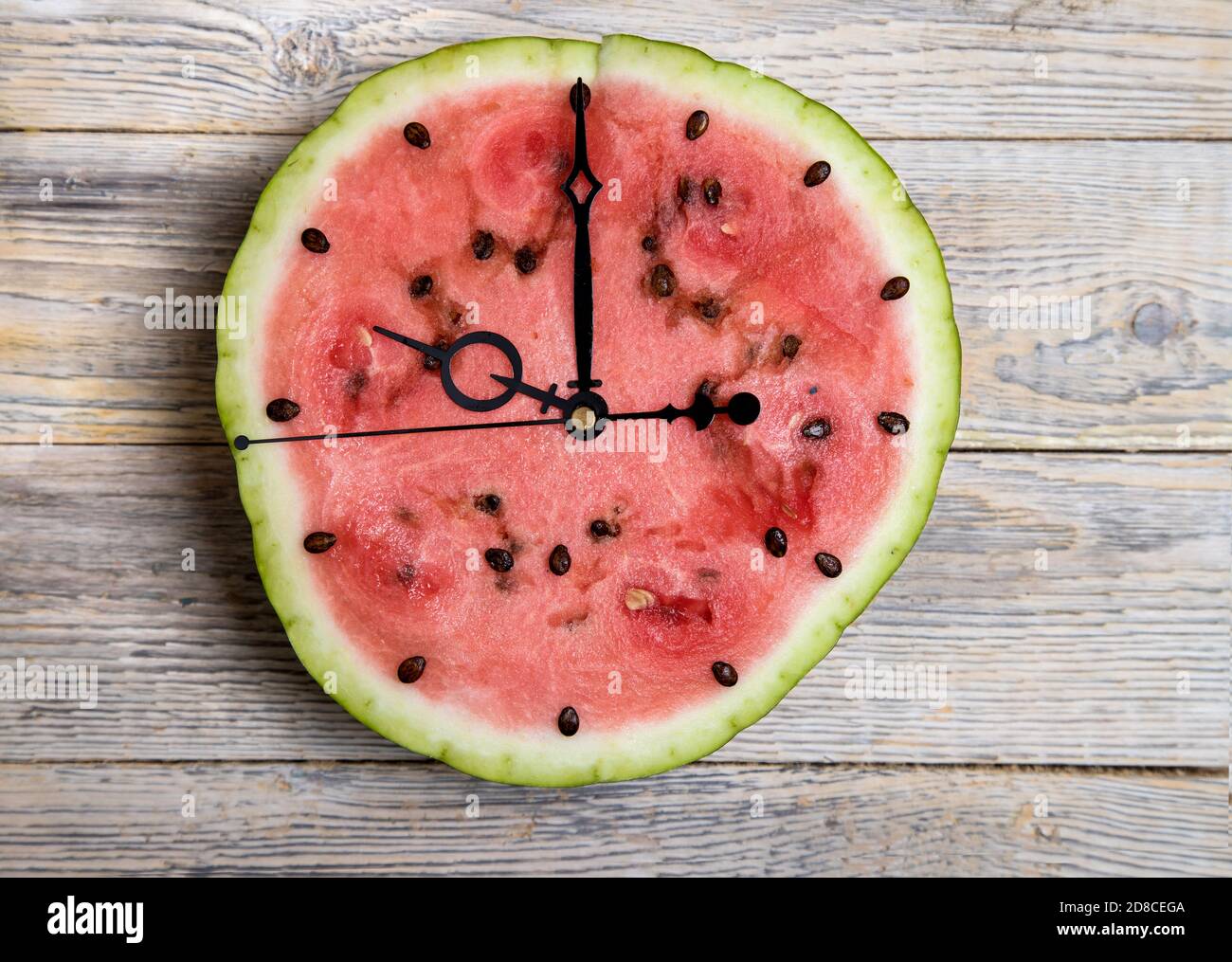 Watermelon slice with arrows showing ten o'clock, light wooden ...