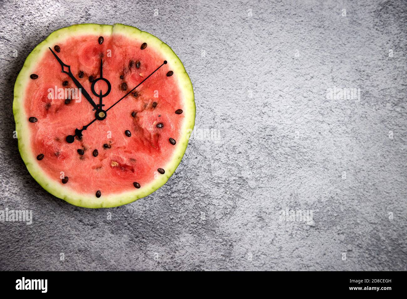 Cut of a ripe watermelon in the form of a clock, the hands show twelve ...
