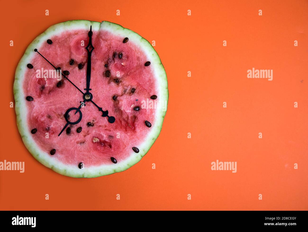 Slice of a ripe watermelon in the form of a clock, the hands show seven ...
