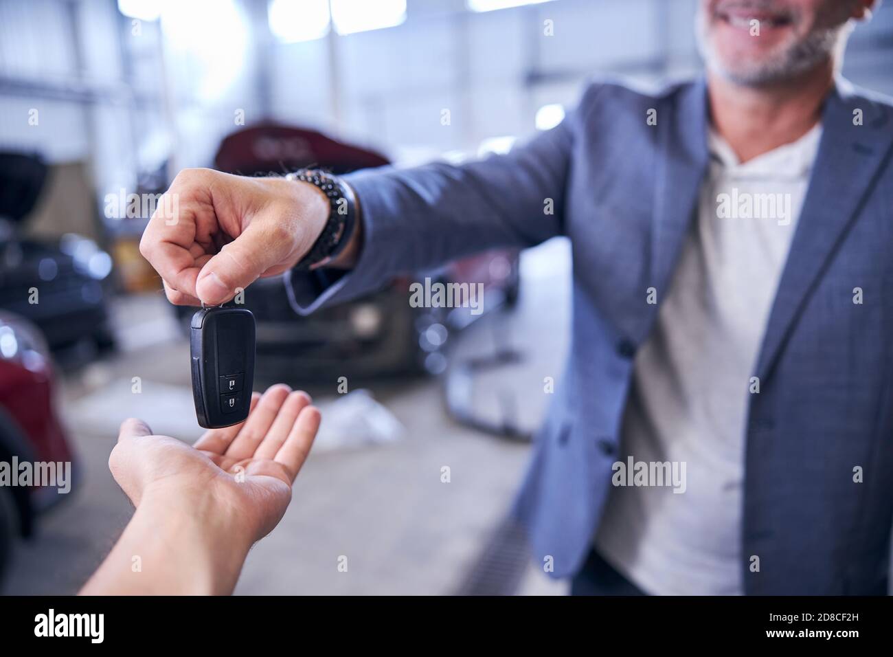 Cheerful man giving smart car key to mechanic at service station Stock ...