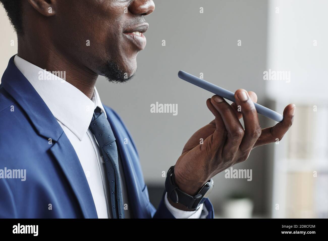 Close-up of African man in suit holding mobile phone and talking on it ...