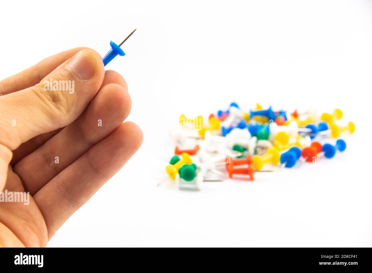 Man holding a sharp stationery pin in his hand on white isolated ...