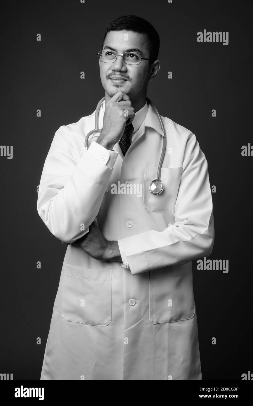 Young multi ethnic Asian man doctor against gray background Stock Photo ...