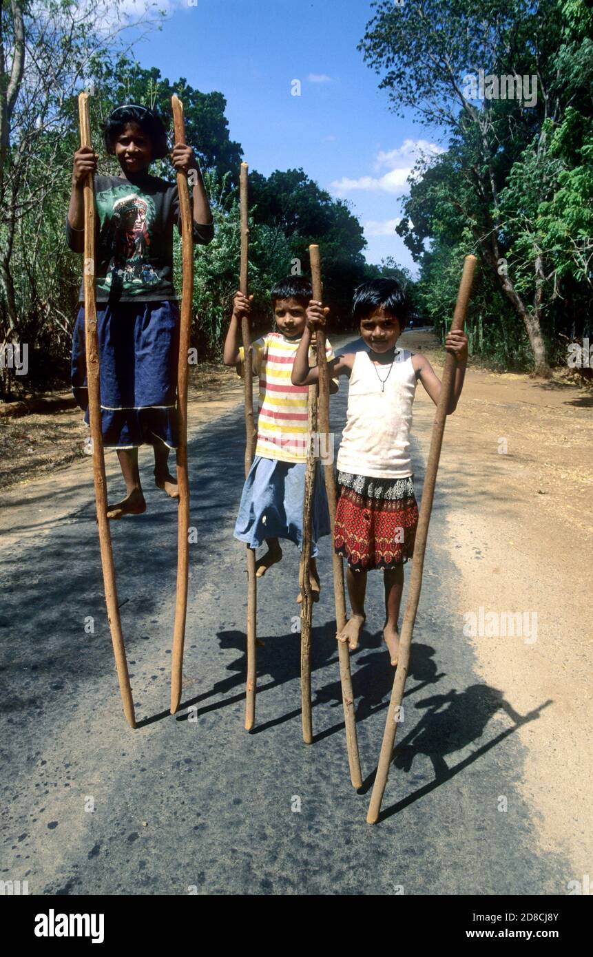 Three children on stilts on a rural road in Sri Lanka. Stilt walking is ...