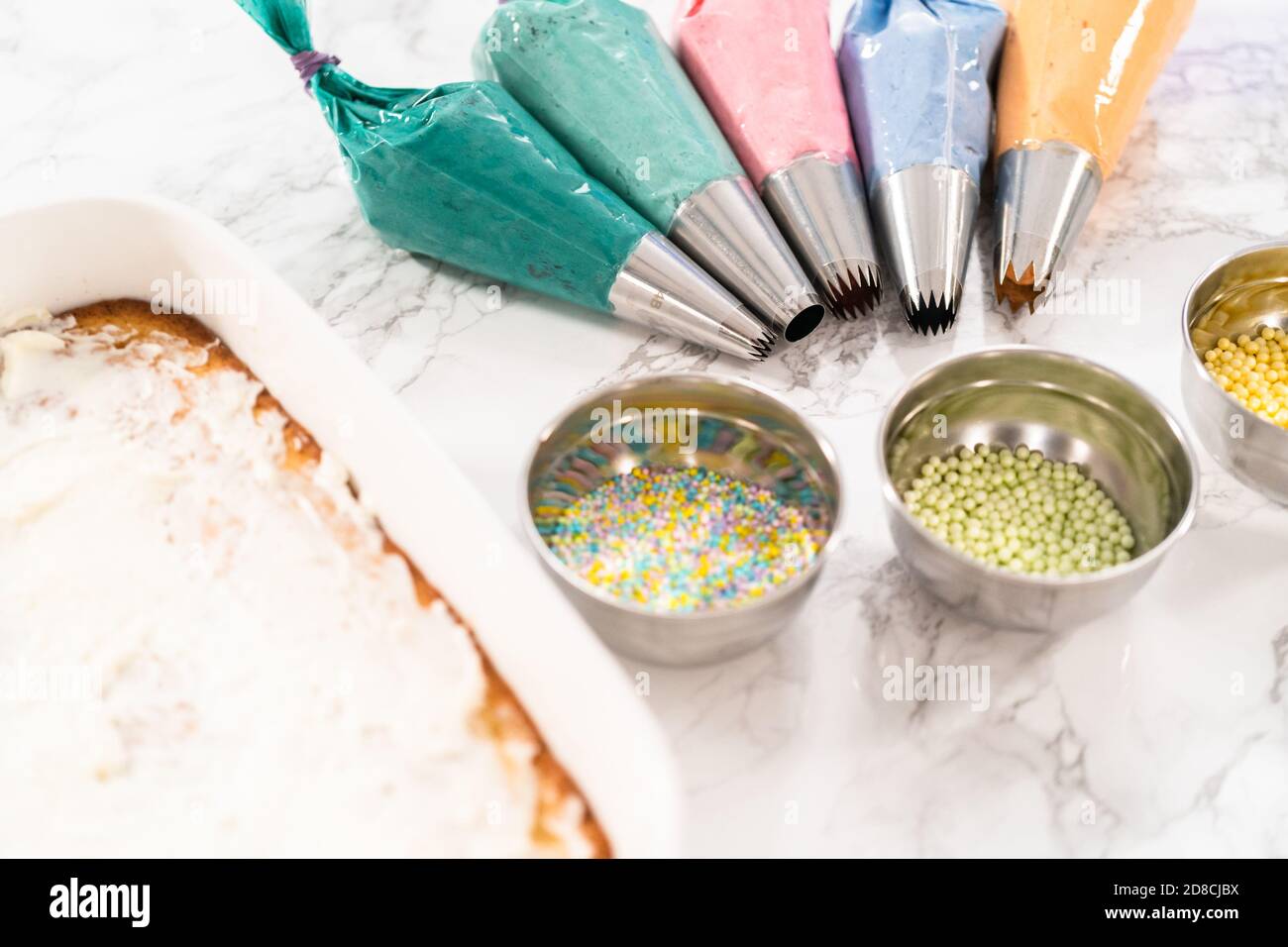 Piping bag with metal tips filled with colorful Italian buttercream ...