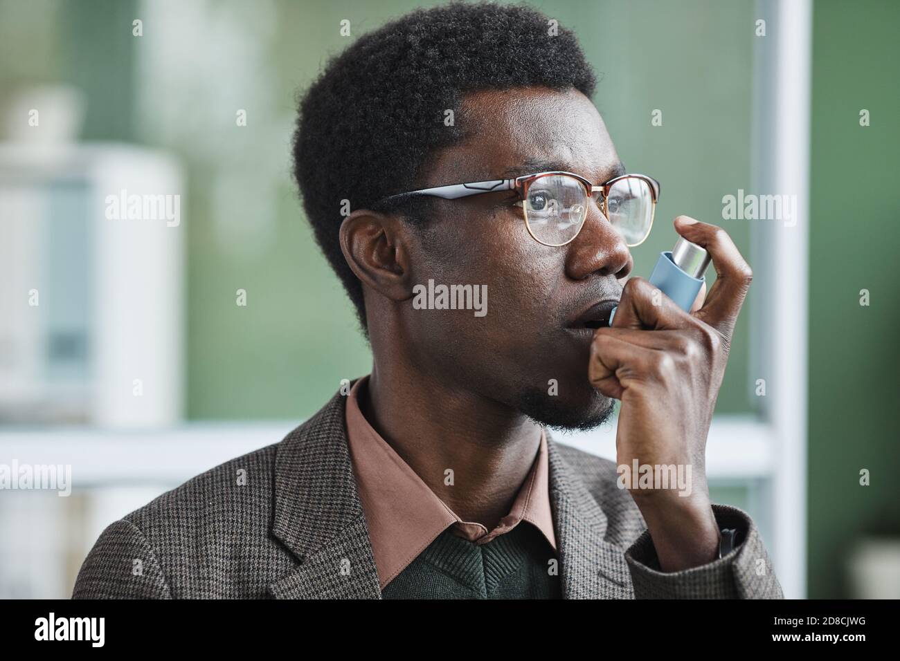 African young businessman using inhaler during work at office he has ...