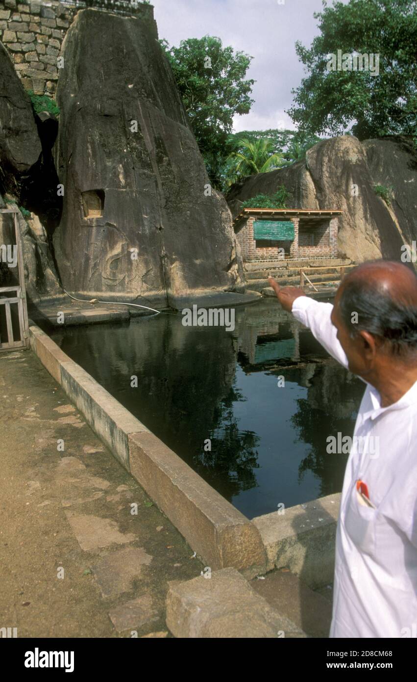 A guide points out a rock carving at Isurumuniya Vihara rock temple at the ancient Buddhist ...