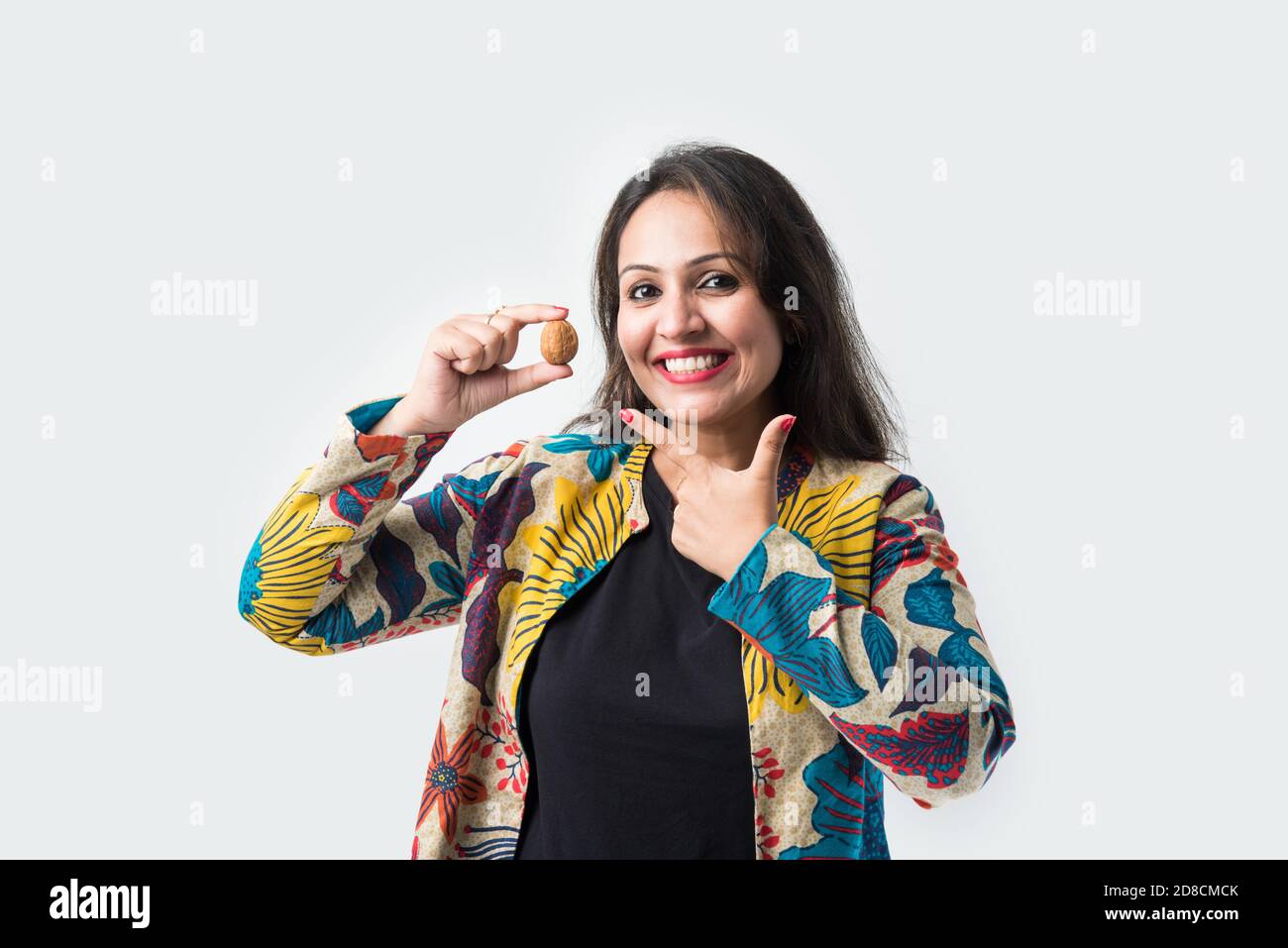 Pretty Asian Indian young girl showing dry fruits like Cashew, Almond ...
