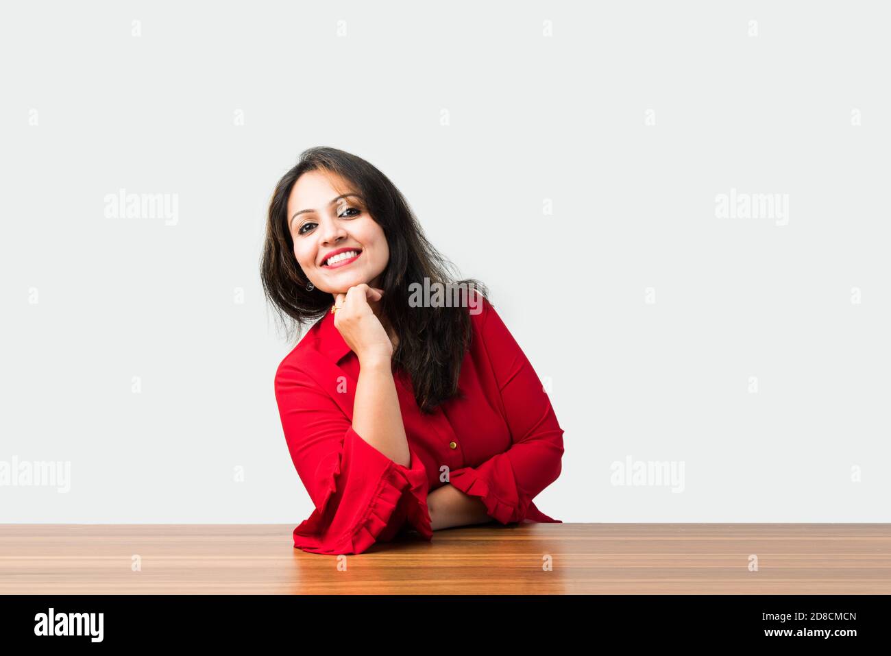 Indian asian pretty woman standing at table resting chin on hands Stock ...