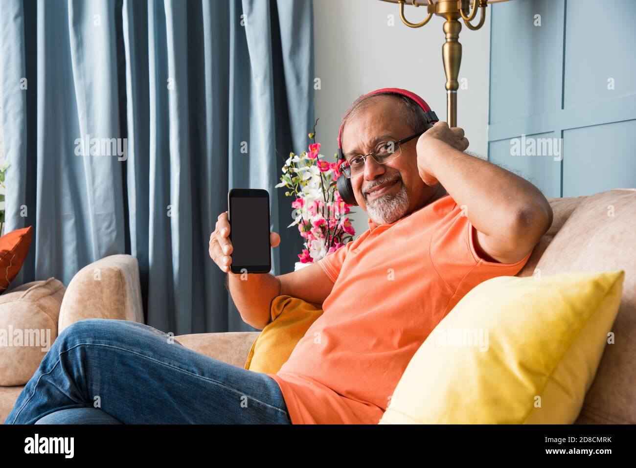Indian asian old man using headphones while listning to music or ...