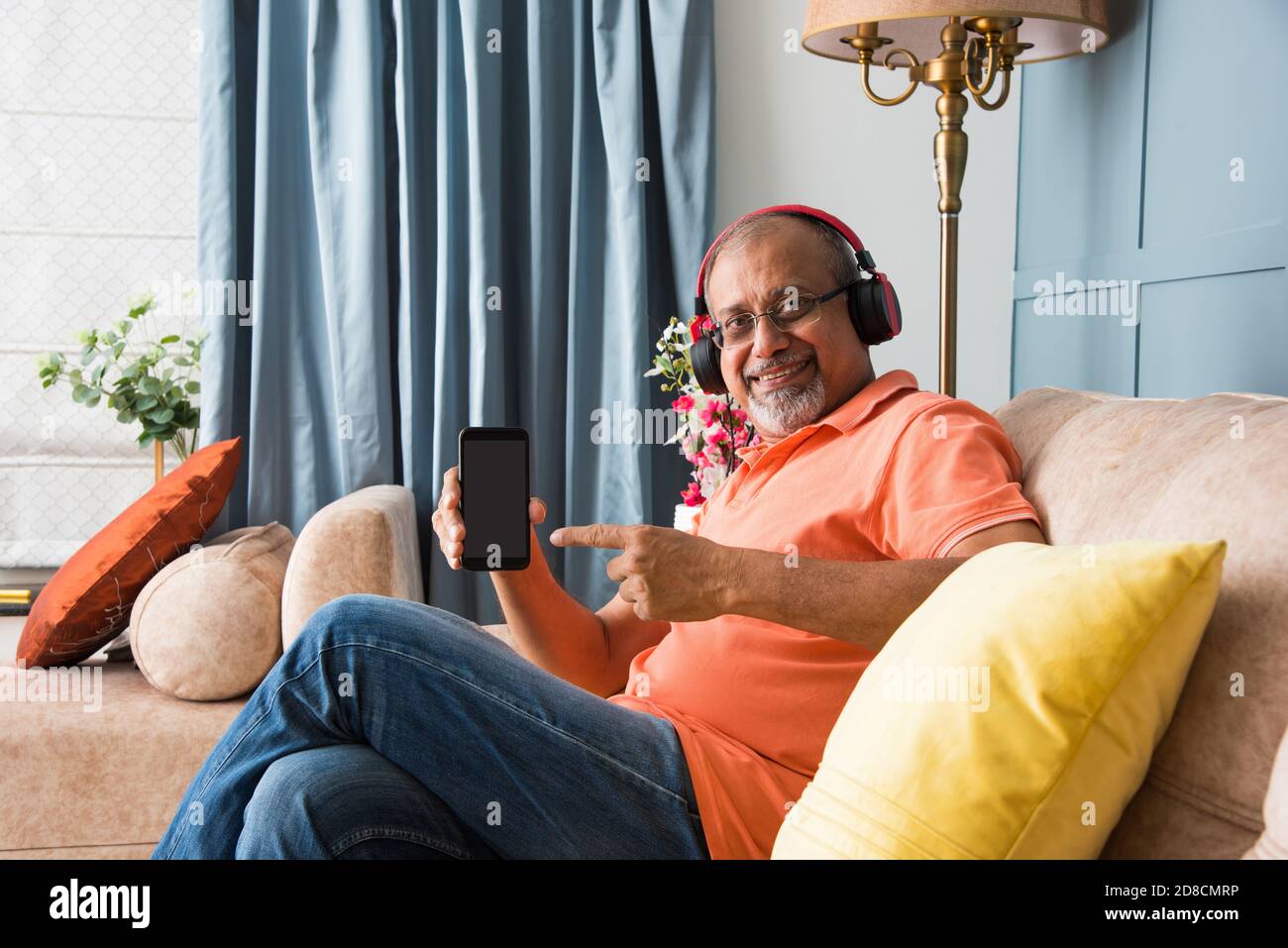 Indian asian old man using headphones while listning to music or ...