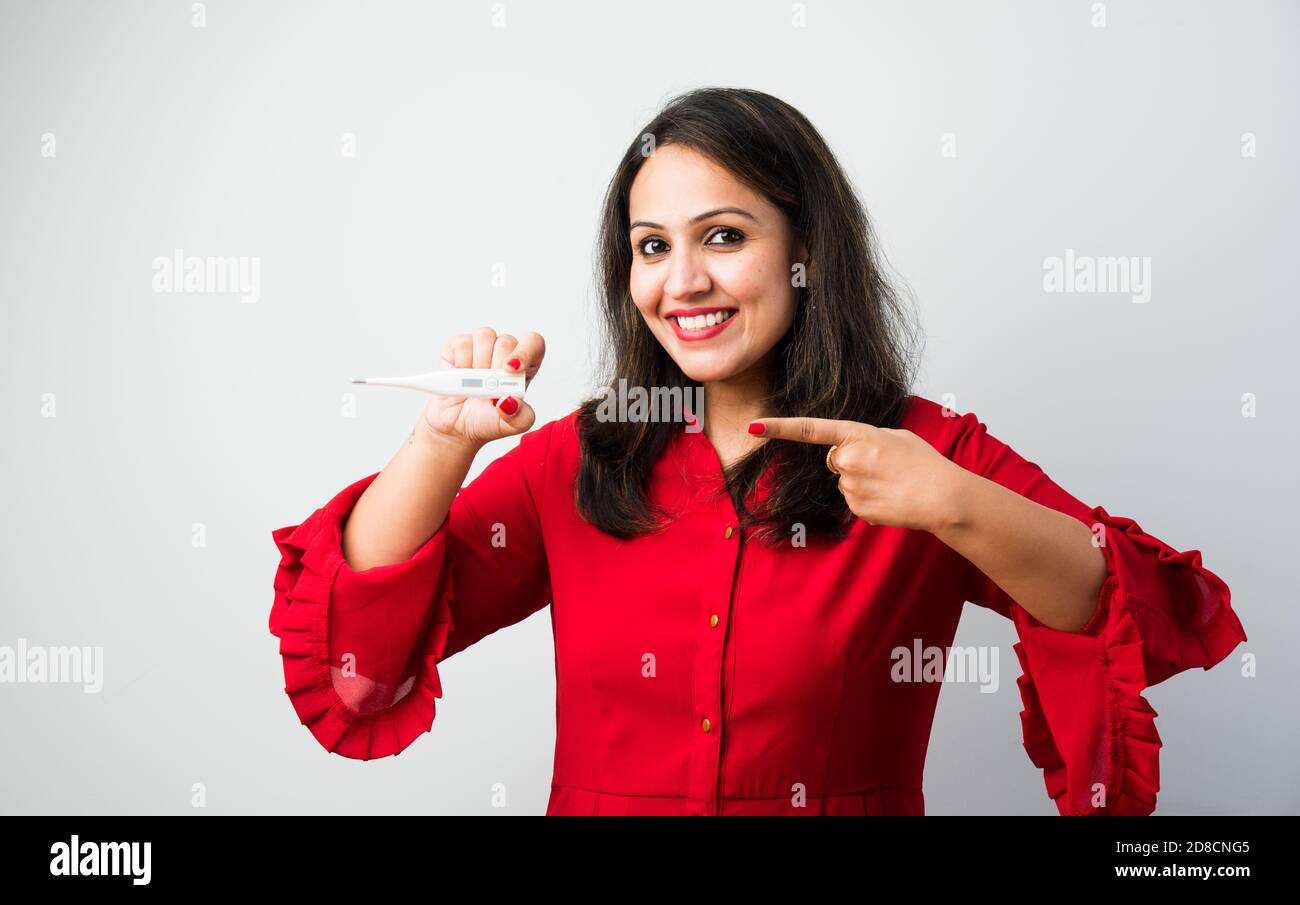 Indian asian young woman checking temperature with thermometer or ...