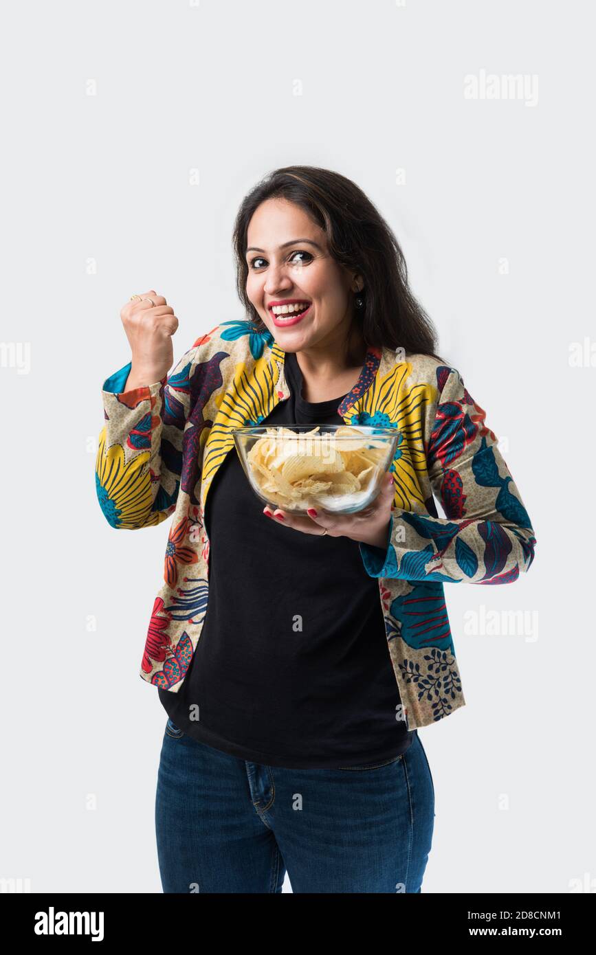 Indian asian pretty young girl eating potato chips on white background ...