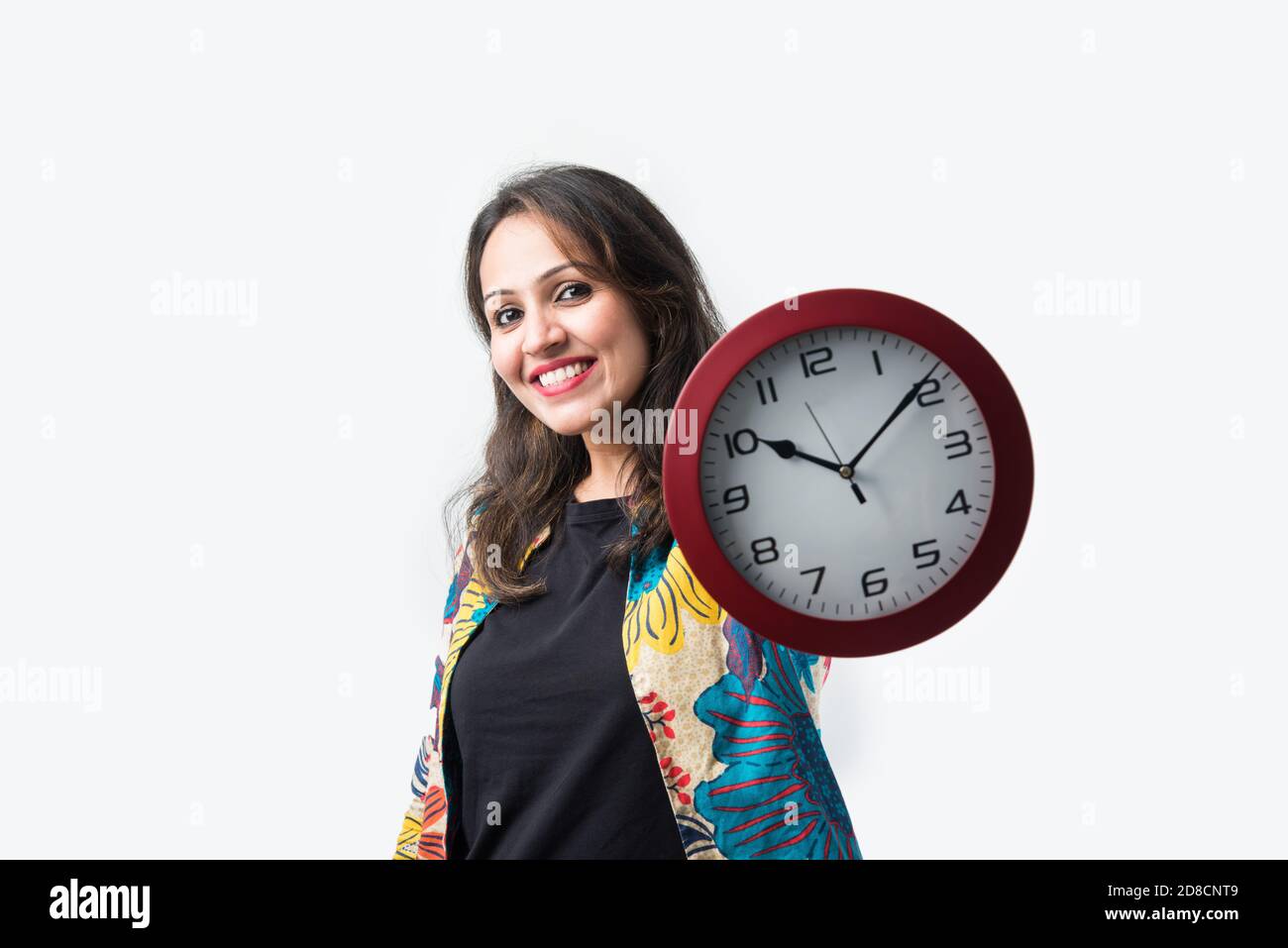 Pretty Asian Indian woman or young lady holding round wall clock - time ...